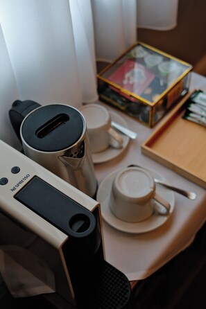 Uma cafeteira, xícaras, uma caixa e uma bandeja com uma colher sobre uma mesa.