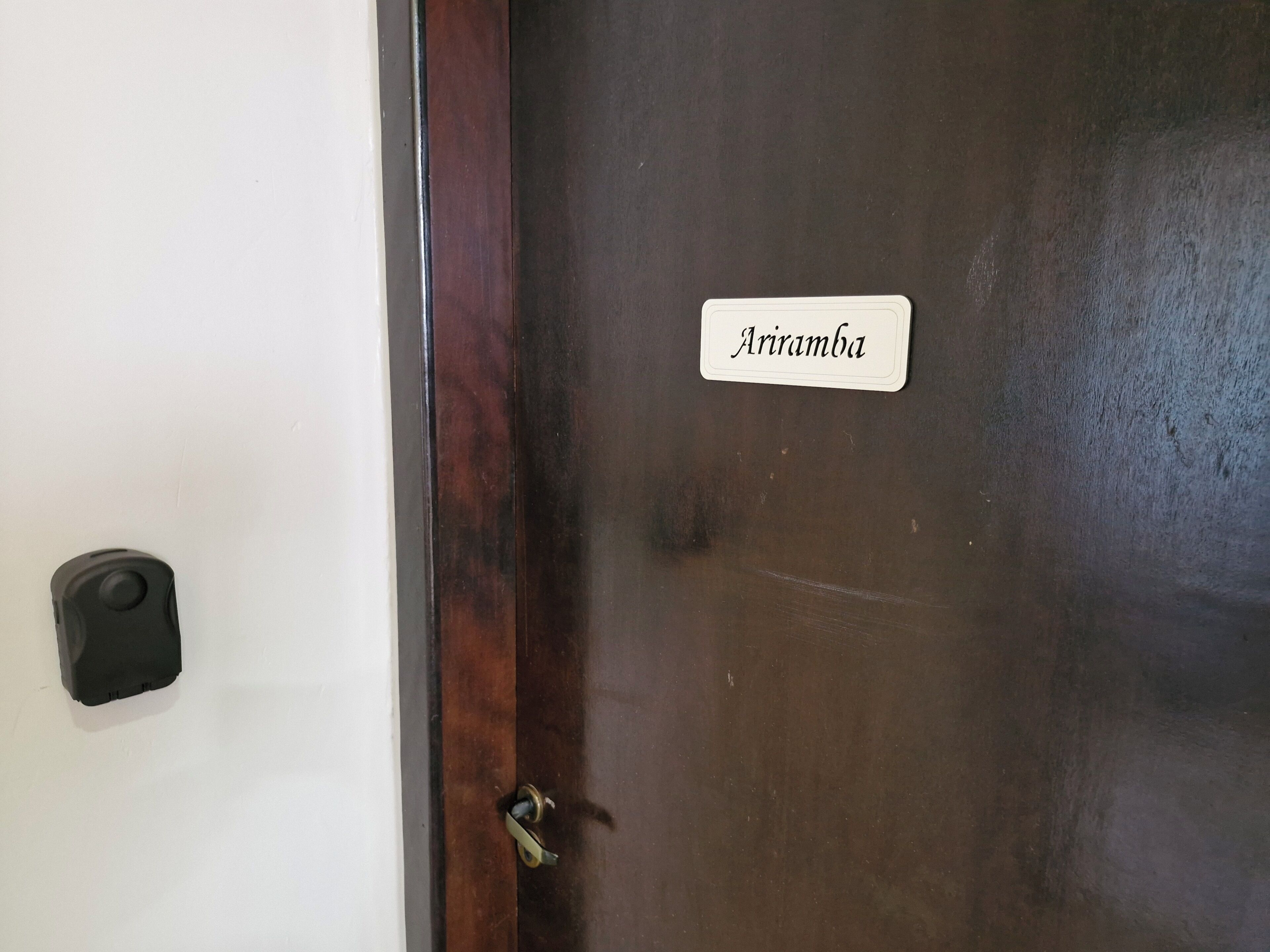 Uma porta com uma placa de identificação que diz 'Arinamba' e uma fechadura.