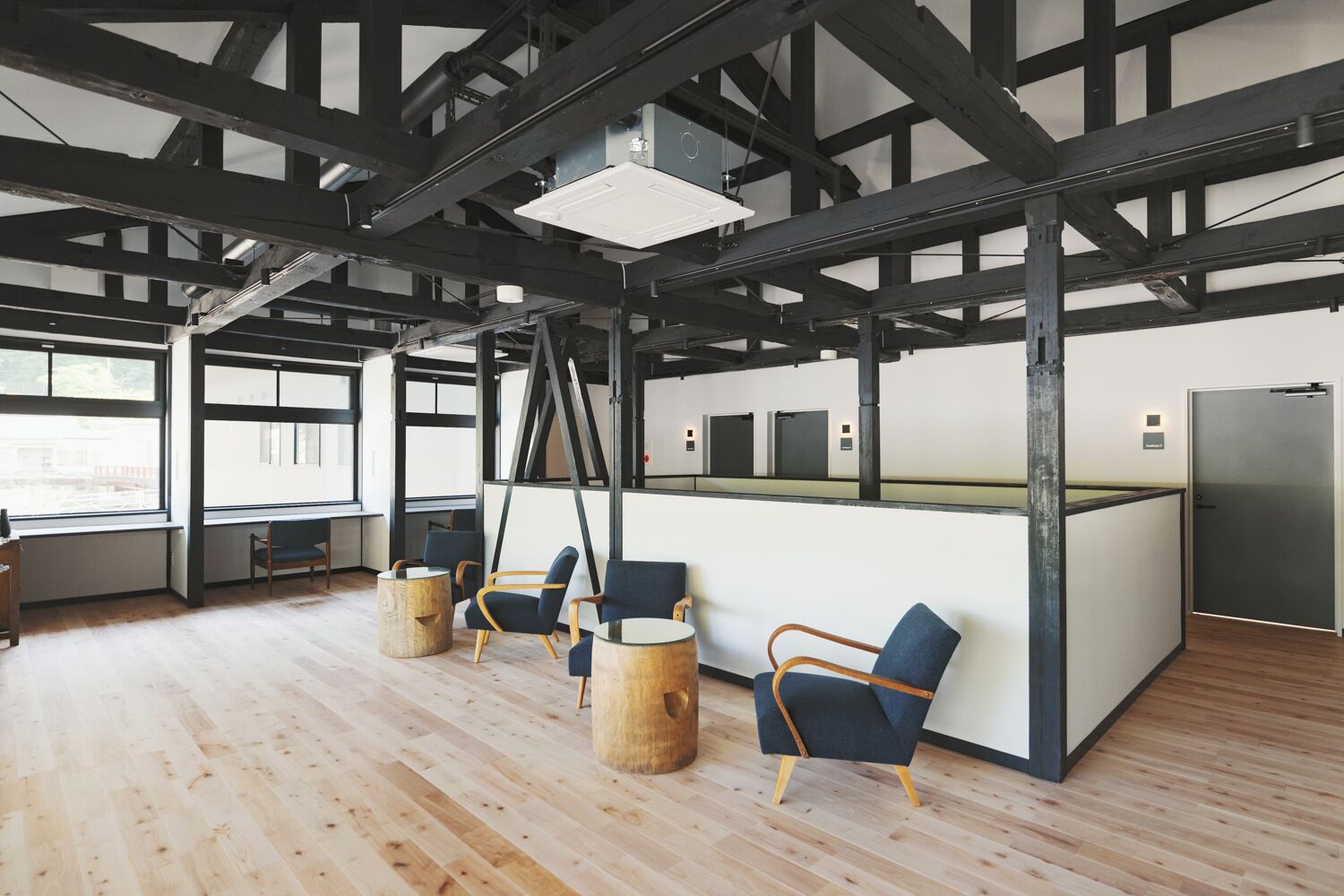Um espaço interior com vigas aparentes, balcão de recepção e áreas de estar.