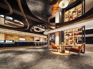 Uma área de bar moderna com um balcão comprido, banquetas e um espaço de estar com uma mesa redonda e cadeiras.