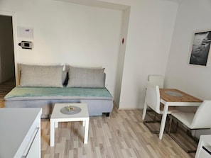 Uma sala de estar moderna com um sofá, uma pequena mesa e uma mesinha de madeira.