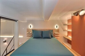 Quarto moderno com cama, mesas de cabeceira e estantes embutidas.
