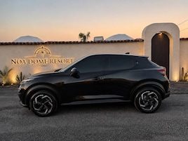 Um SUV preto estacionado em frente a um edifício com uma placa que diz 'NOA DOME RESORT'.