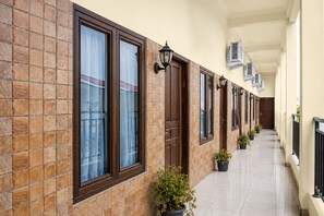Um corredor com parede revestida de azulejos, várias janelas e aparelhos de ar condicionado.