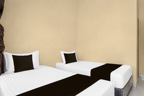 Quarto de hotel com duas camas de solteiro, cada uma com roupa de cama branca e um cobertor preto.
