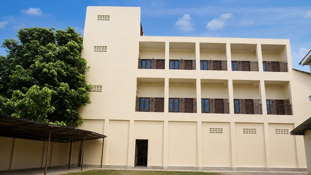 Um edifício de vários andares com fachada plana, várias varandas e área de entrada coberta.