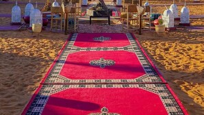 Decoração de casamento no deserto, com tapete vermelho que conduz a um altar enfeitado.