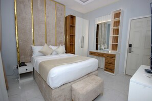 Quarto com cama, mesa de cabeceira, guarda-roupa e penteadeira com espelho.