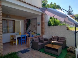 Um pátio externo com mesa, cadeiras e móveis de vime.