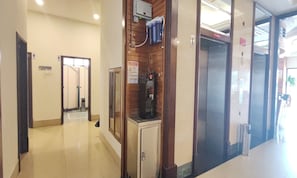 Um corredor com um bebedouro, um alarme de incêndio e uma porta identificada como 'LF BOWSA'.