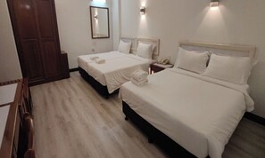 Quarto de hotel com duas camas, um guarda-roupa de madeira, um espelho e uma mesa de cabeceira com telefone.