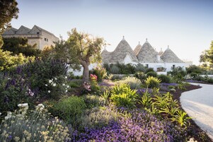 Um jardim com diversas flores e um edifício com telhados cônicos.