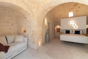 Quarto com parede de pedra, um sofá, uma cama e uma luminária moderna.