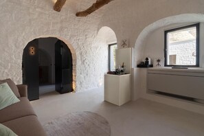 Um interior moderno com parede de pedra, um sofá, uma mesa redonda e uma janela com vista.