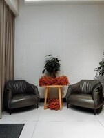 Um quarto com dois sofás de couro, uma mesinha de madeira com folhagem vermelha e uma planta em vaso.