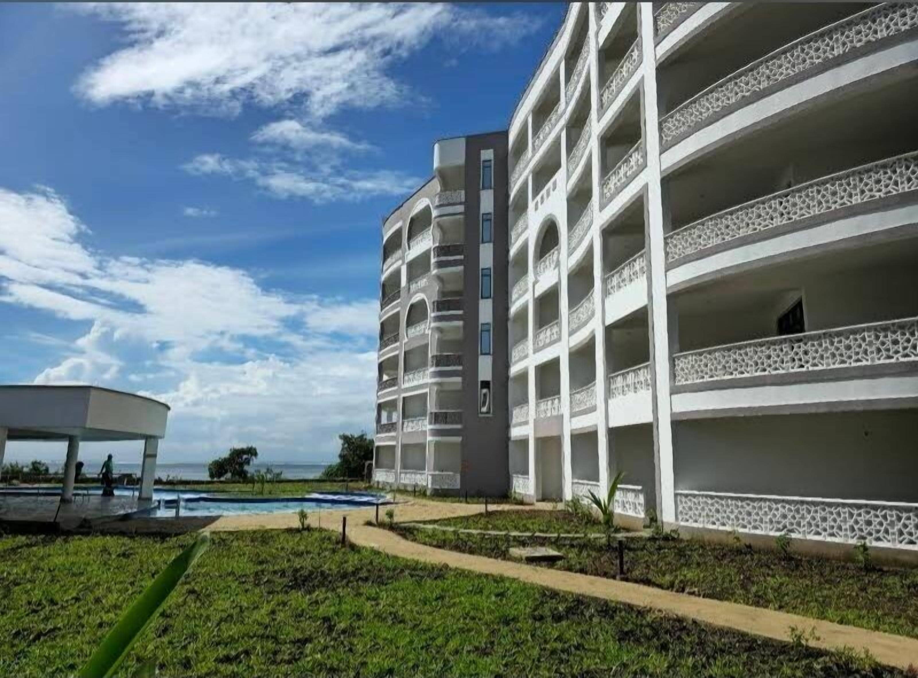 Um edifício com várias andares, varandas, área de piscina e céu claro.