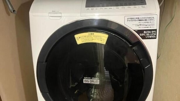 Máquina de lavar com carga frontal, painel de controle e etiqueta na porta.