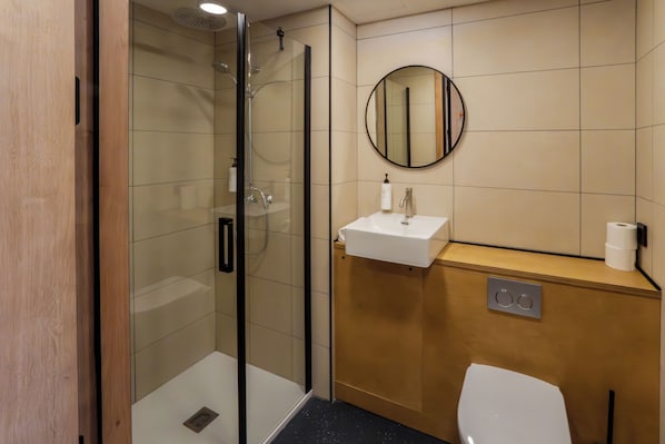 Um banheiro moderno com box de vidro, pia com espelho e vaso sanitário.