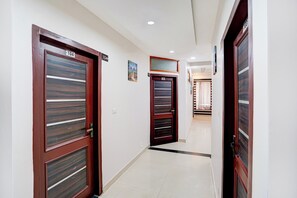 Um corredor com portas de madeira numeradas 104 e 105, que dá para um quarto com cama e janela.