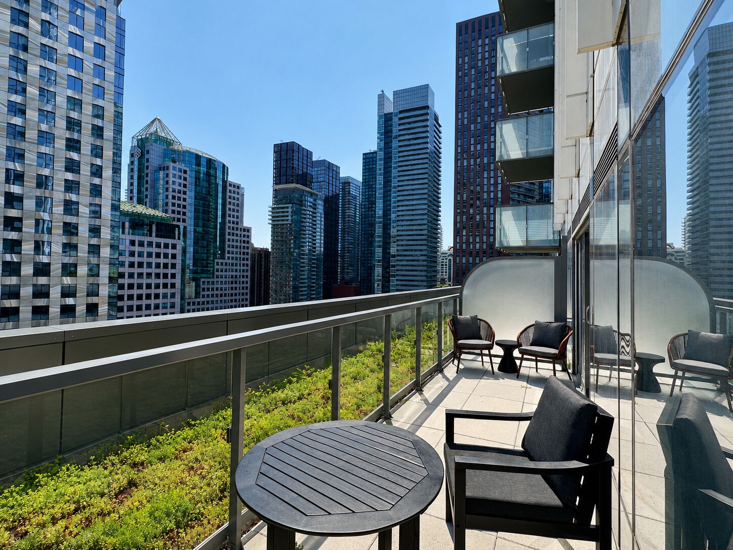 Terraço no telhado com vista para edifícios altos, mobiliado com assentos externos e uma mesa pequena.