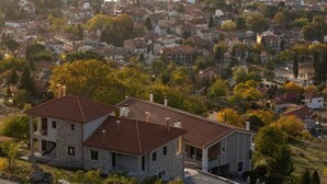 Uma área residencial com casas, incluindo uma casa de pedra com telhado vermelho, e vista para o bairro ao redor.