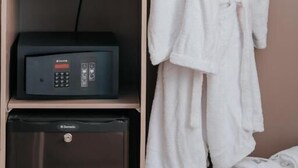 Quarto de hotel com minibar, máquina de café e roupão pendurado em um suporte.