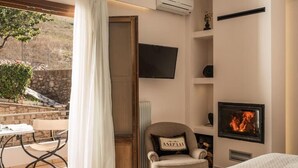 Quarto com cama, lareira, televisão e vista para o exterior.