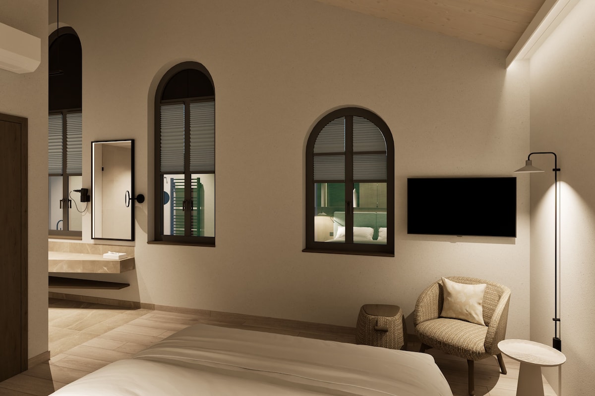 Quarto com cama, duas janelas, uma cadeira, mesa de cabeceira, televisão de tela plana e abajur.