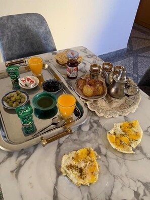 Bandeja de café da manhã com ovos, torradas e bebidas sobre uma mesa de mármore.