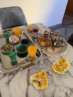 Bandeja de café da manhã com ovos, torradas e bebidas sobre uma mesa de mármore.