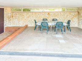 An outdoor patio with a stone wall, a table with chairs, and a small step leading to a door.