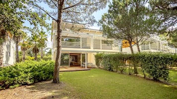 Uma casa moderna com varanda coberta, gramado e diversas árvores.