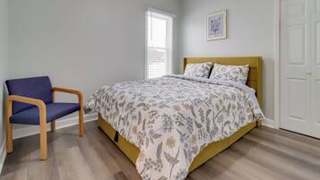 Um quarto com uma cama, uma cadeira, uma janela e uma porta.