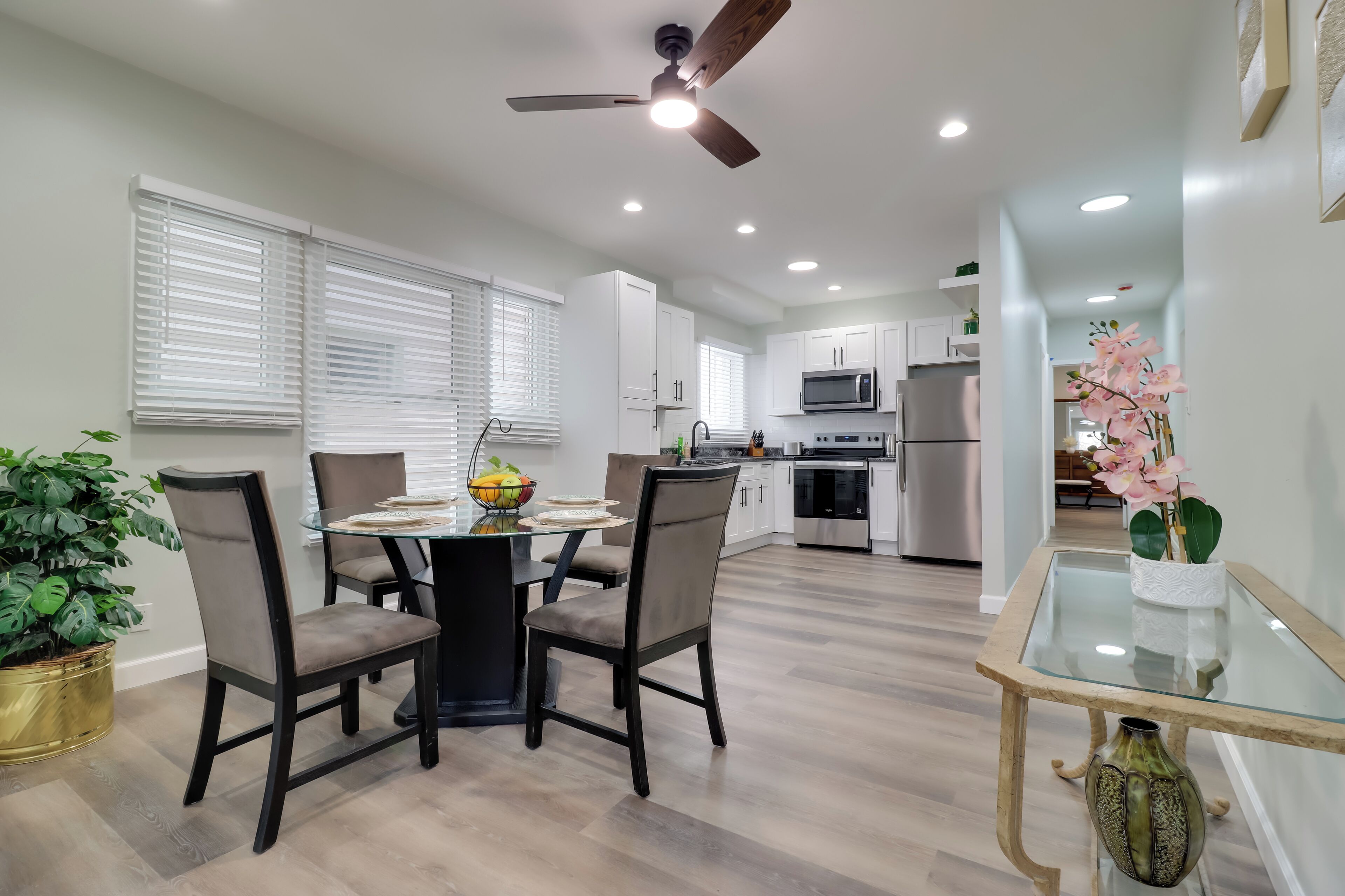 Uma cozinha moderna com armários brancos, micro-ondas e geladeira de aço inoxidável.