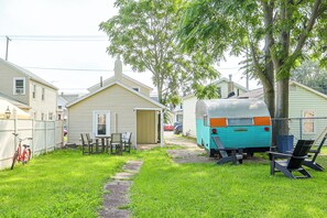 Um bairro residencial com uma casa pequena, uma casa móvel azul e um gramado.
