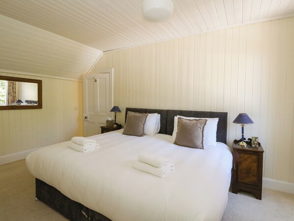 Quarto com cama grande, duas mesas de cabeceira, um espelho e uma porta.