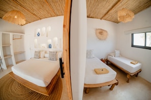 Quarto com uma cama grande, uma cama menor, uma janela e um guarda-roupa.