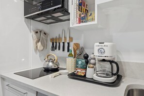 Uma cozinha com cafeteira, chaleira e jarra de café no balcão.