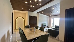 Quarto de hotel moderno com área de refeições, televisão e sofá.