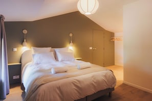 Um quarto com cama, abajures, guarda-roupa e luminária pendente.