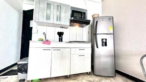 Uma cozinha compacta equipada com micro-ondas, geladeira e fogão a gás.