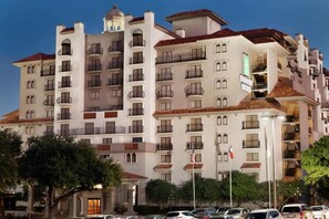 Hotel com vários andares, varandas, uma bandeira e uma placa indicando 'Entrance Suites'.