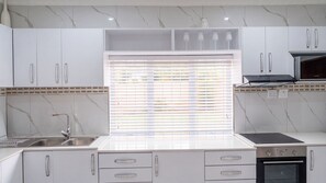 Uma cozinha moderna com armários brancos, uma pia de aço inoxidável e um forno embutido.