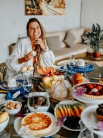 Uma mesa de jantar com vários pratos e uma pessoa sentada.