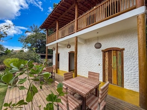 Um edifício de dois andares com varanda, área de estar externa e um jardim.