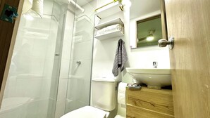 Uma casa de banho com sanita branca, lavatório, porta-toalhas e zona de duche.