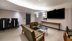 A conference room with a large flat-screen TV, a table, and several chairs.