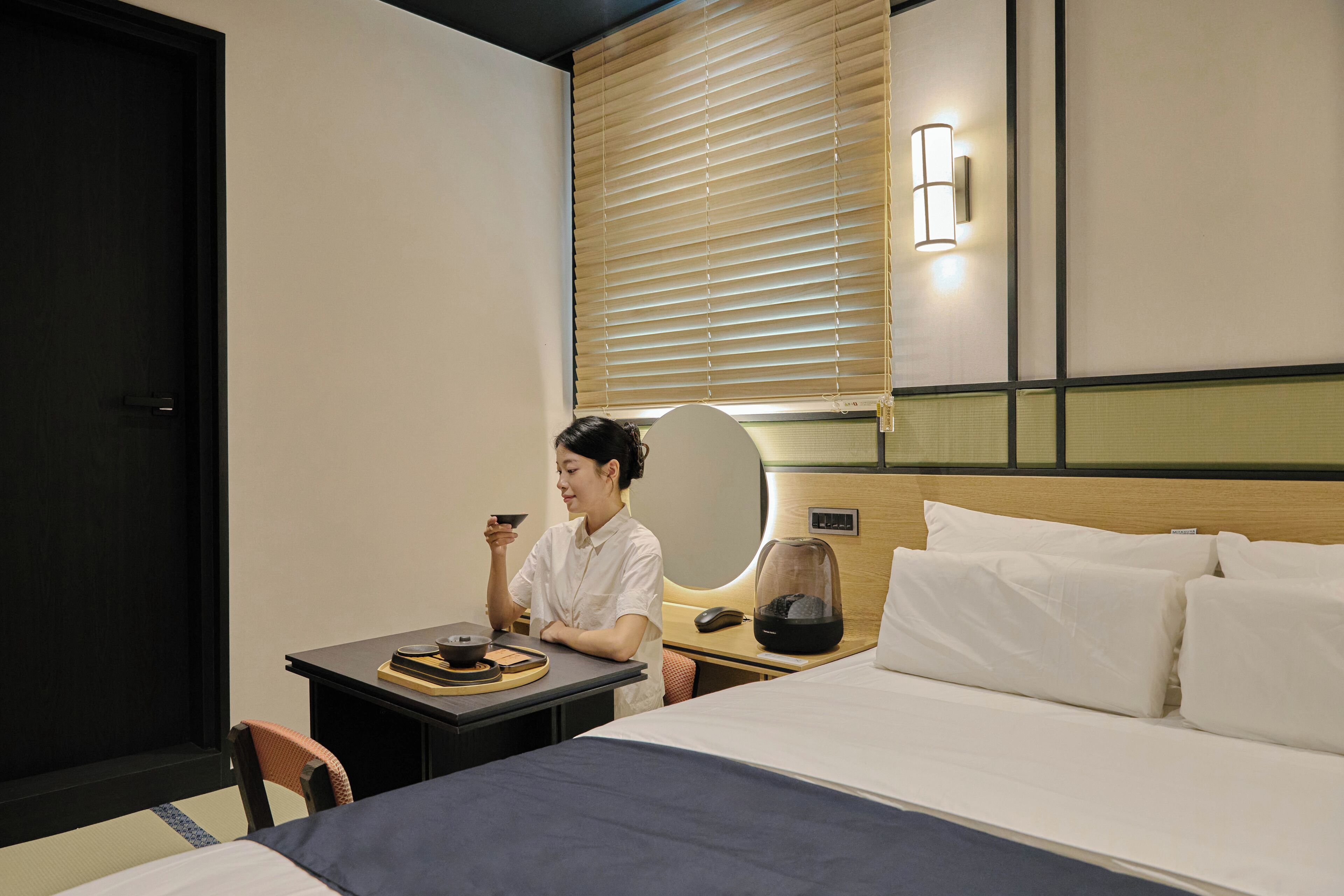 Quarto de hotel com cama, mesa de cabeceira e uma cadeira.