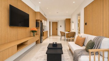 Uma sala de estar moderna com um sofá, mesa de centro e televisão na parede.