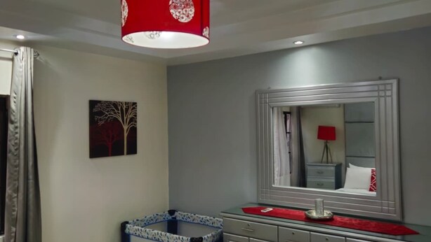 Quarto com cama de solteiro, mesa de cabeceira, espelho e luminária no teto.